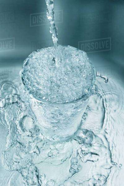Water pouring into an overflowing glass - Royalty-free Stock Photo ...