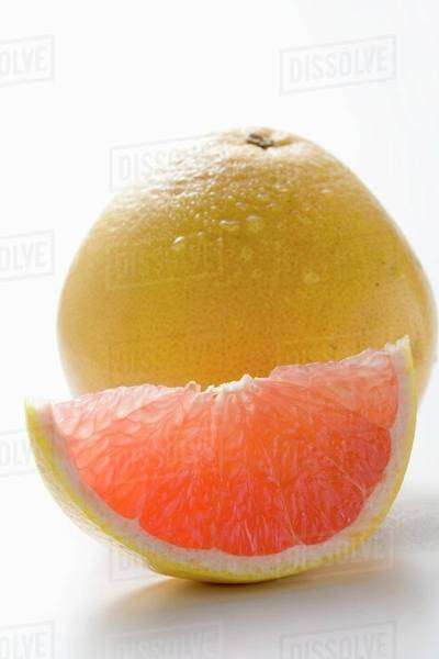 Wedge of pink grapefruit in front of whole grapefruit - Royalty-free ...