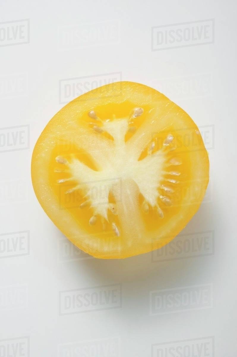 Half a yellow tomato (overhead view) - Stock Photo - Dissolve
