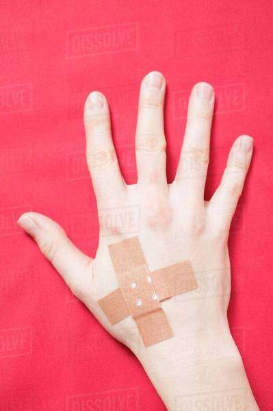 Hand with crossed sticking plasters (overhead view) - Stock Photo ...