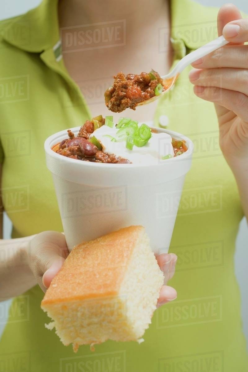 Woman holding chili con carne in paper cup and cornbread - Royalty-free ...