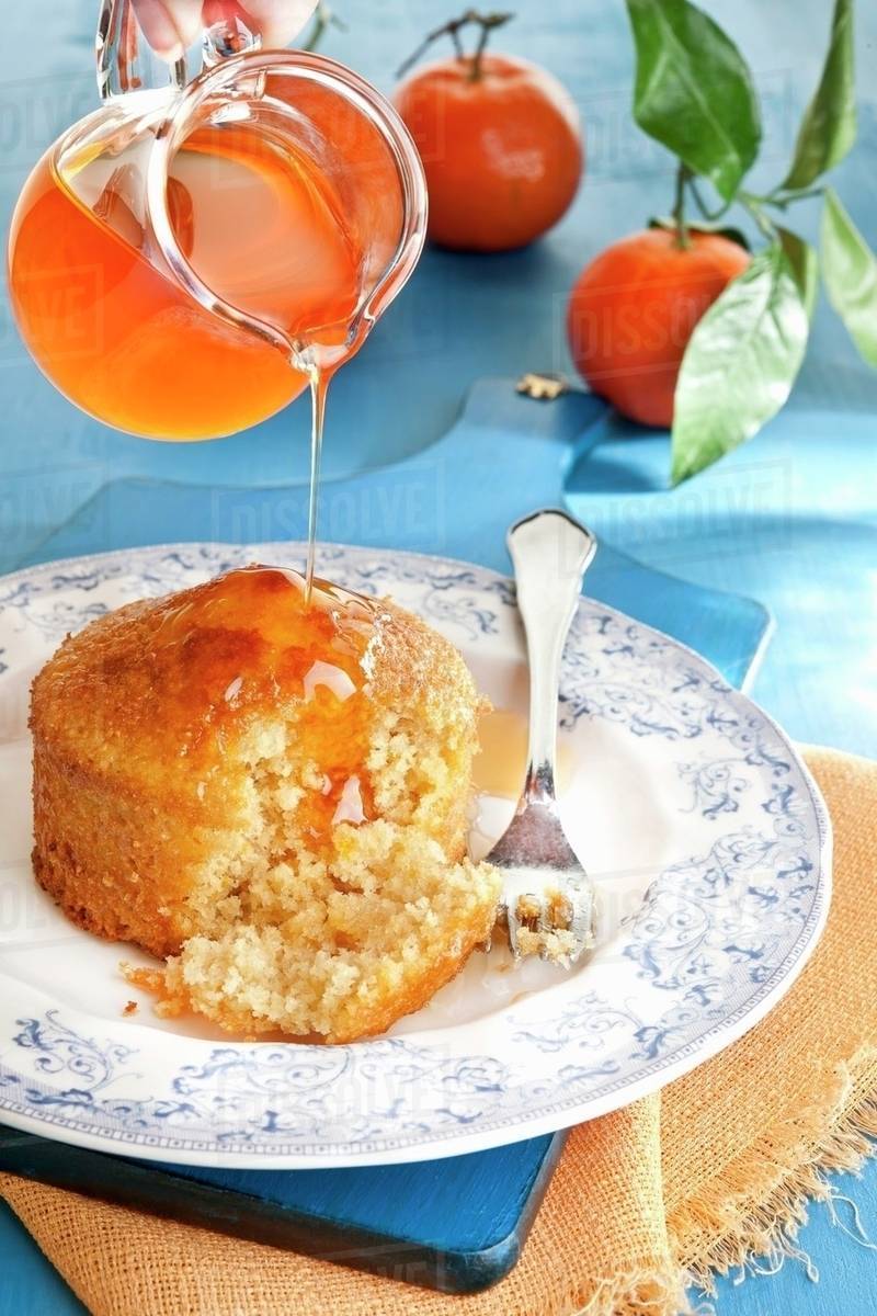 Mandarin syrup being poured over a mini cake - Royalty-free Stock Photo ...
