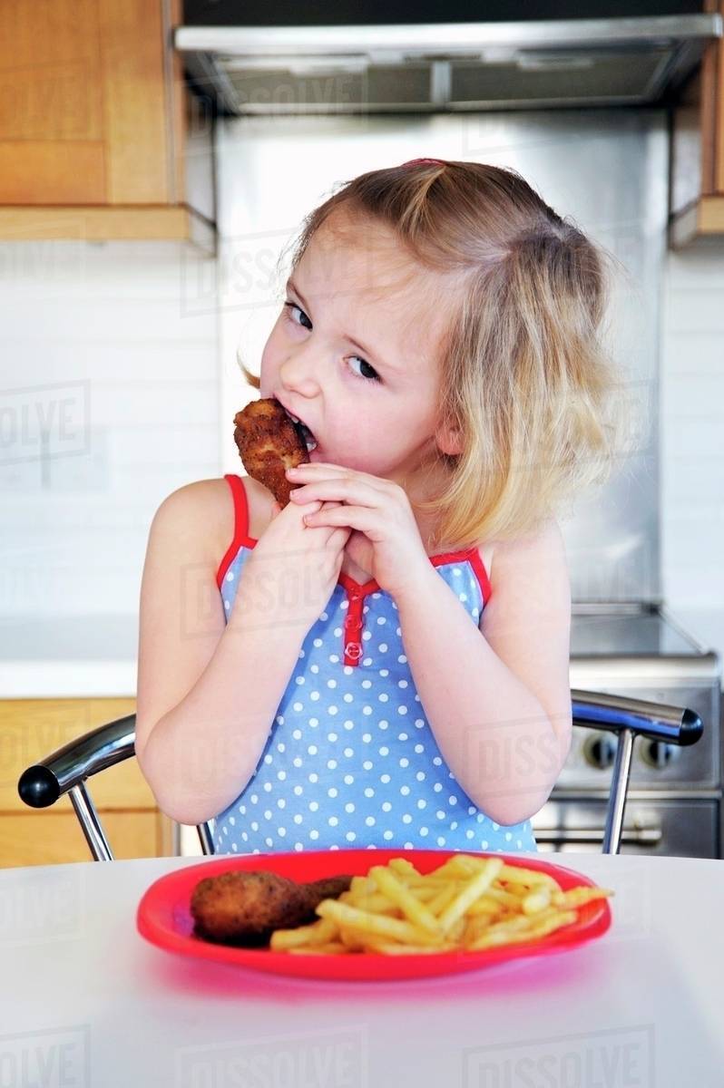 A little girl eating a chicken leg with chips - Royalty-free Stock ...
