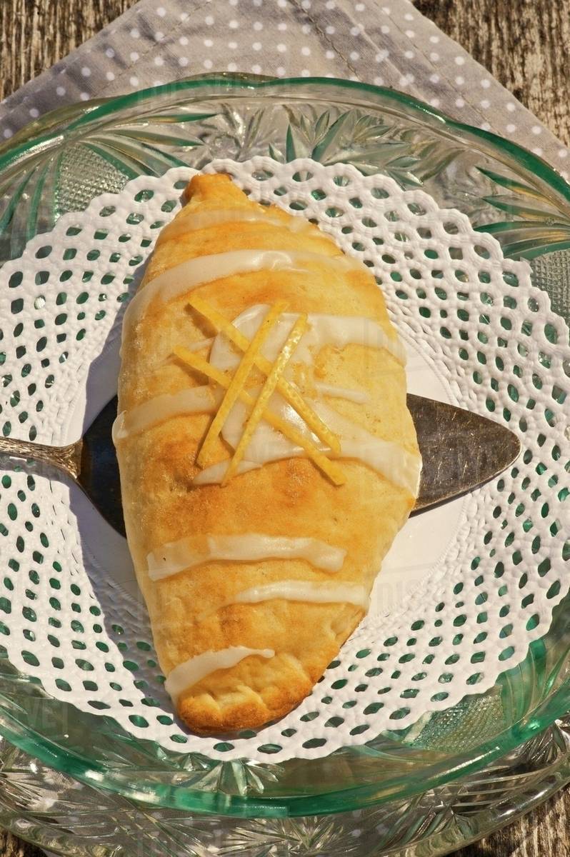 A potato pastry parcel filled with apples and topped with icing sugar ...