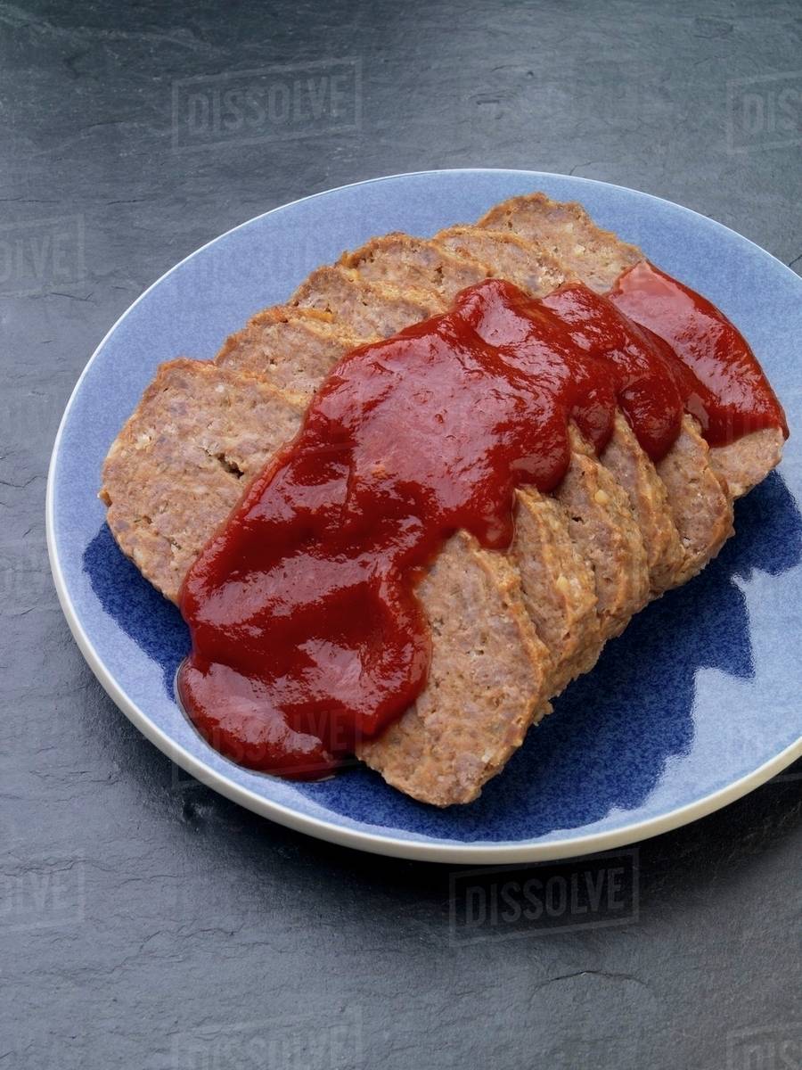 Meat loaf with tomato sauce on a blue plate - Stock Photo - Dissolve
