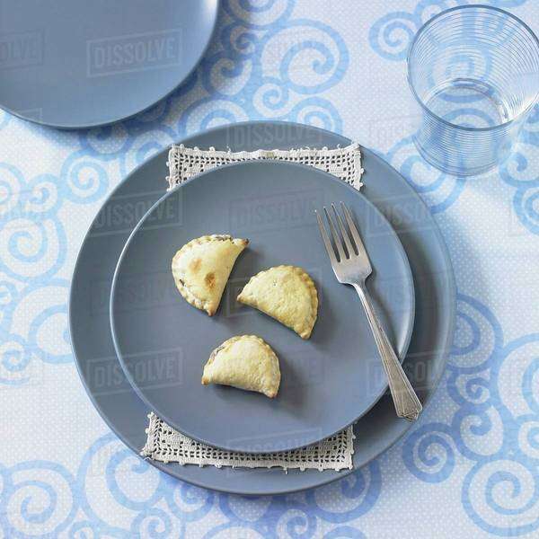 A place setting with blue plates and mushroom filled pastry parcels ...