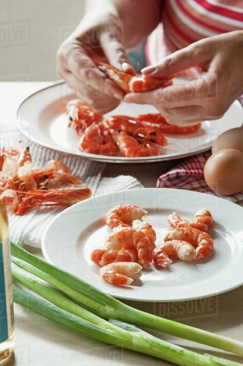 A woman peeling cooked prawns - Stock Photo - Dissolve