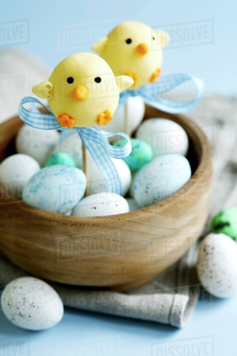 Easter chick cape pops and chocolate eggs in a wooden bowl - Stock ...