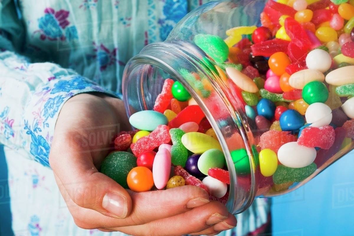 Person tipping sweets out of jar - Royalty-free Stock Photo | Dissolve