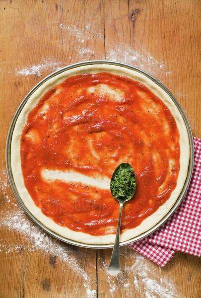 Pizza base with tomato sauce and spoonful of oregano - Stock Photo ...