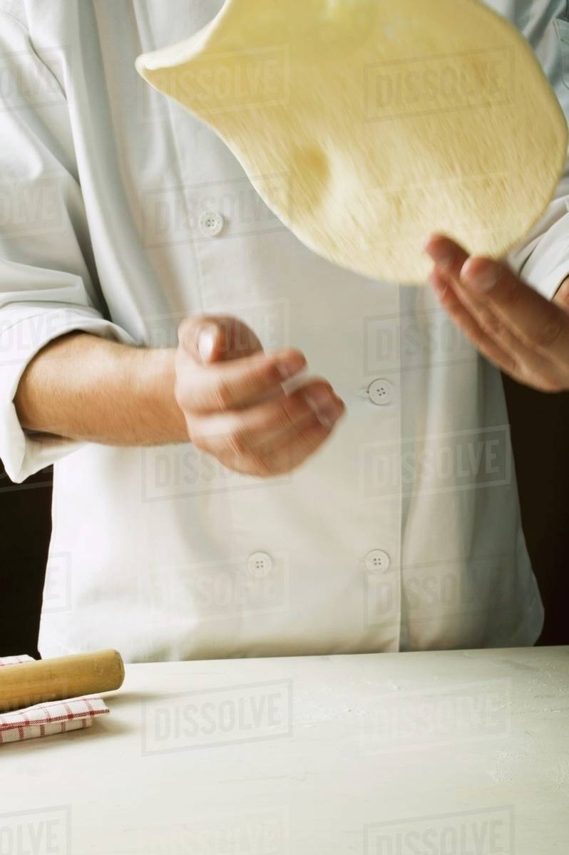 Shaping pizza dough (throwing it in the air) - Stock Photo - Dissolve