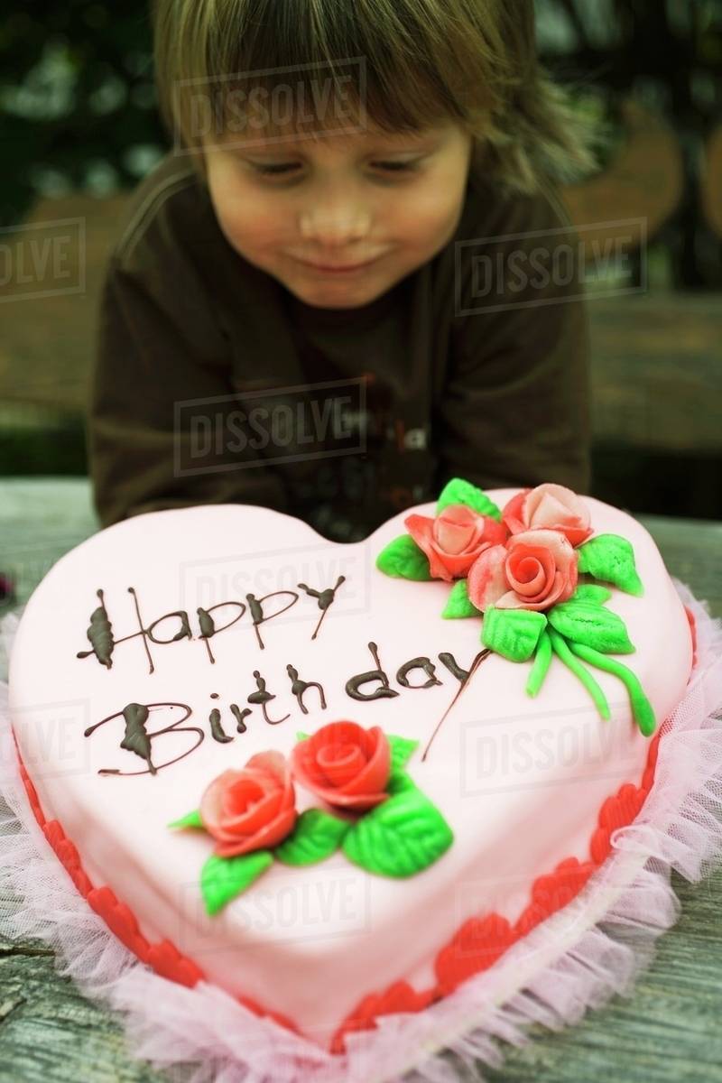 Child with pink heart-shaped birthday cake with marzipan roses ...