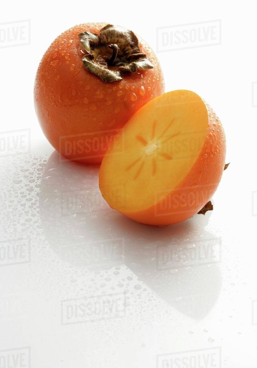 Sharon fruits, whole and halved, with drops of water - Royalty-free ...