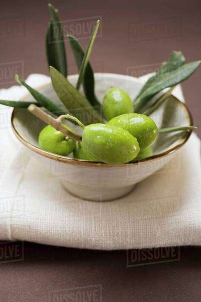 Olive sprig with green olives in bowl on linen cloth - Stock Photo ...