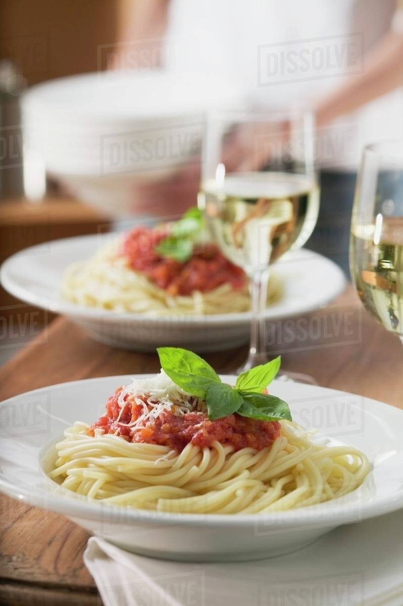 Spaghetti with tomato sauce & glasses of white wine on table - Stock ...