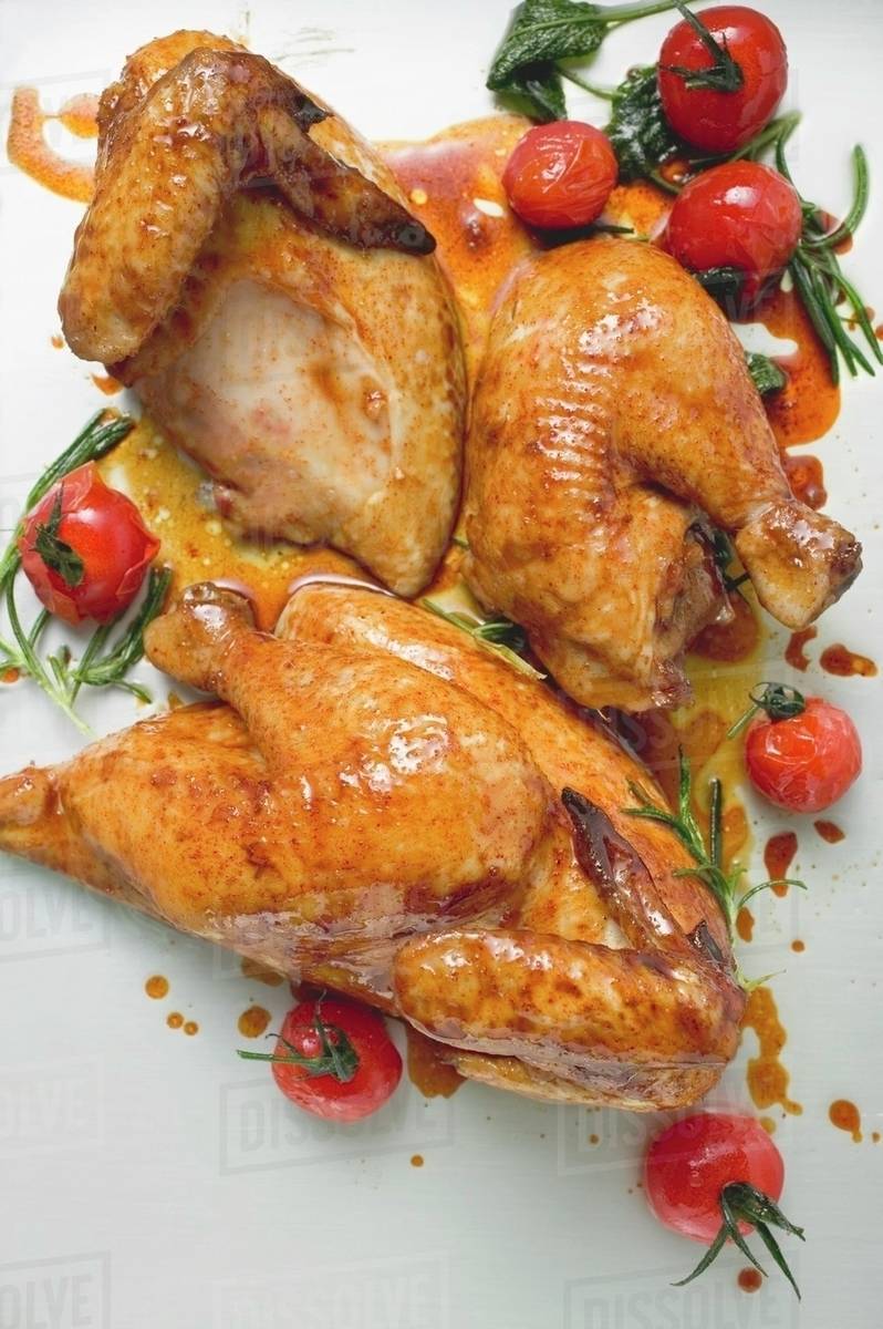 Roast chicken, jointed, with cherry tomatoes - Stock Photo - Dissolve
