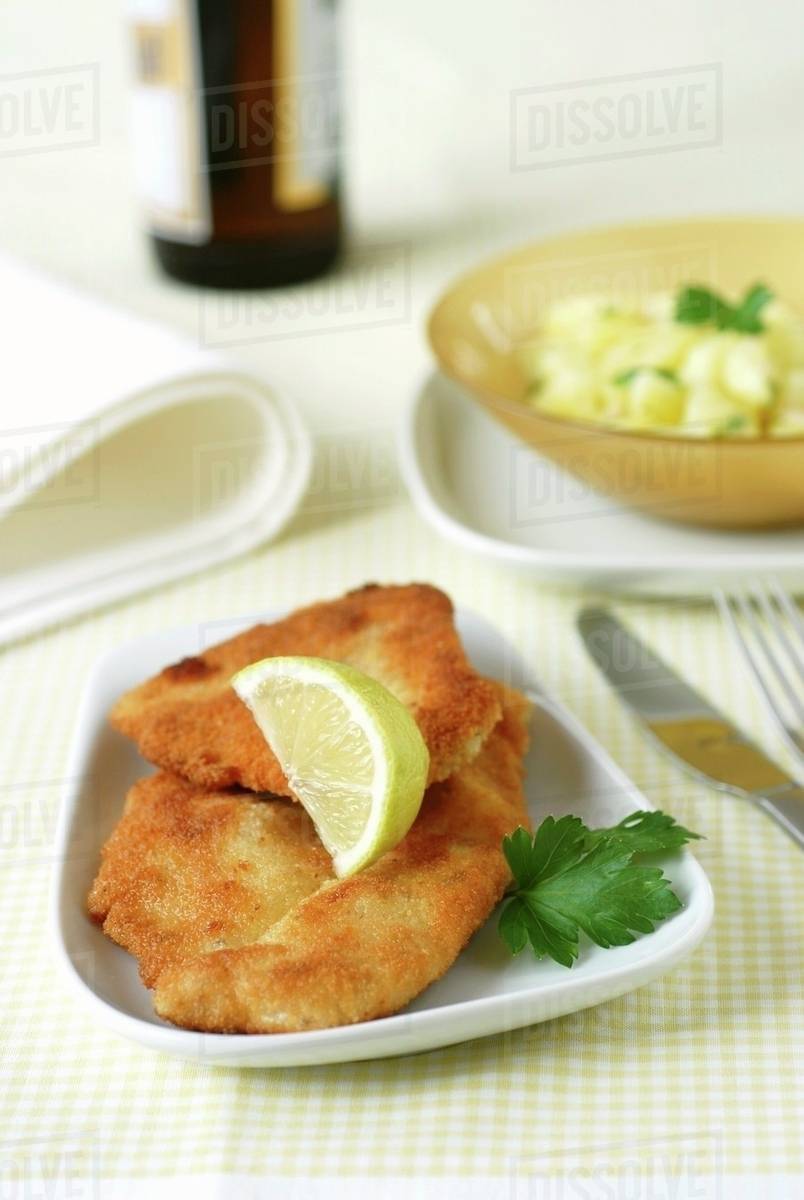 Breaded chicken escalopes, potato salad in background - Stock Photo ...