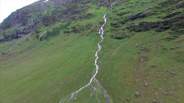 Aerial view of stream of water running down the slope of rocky mountain ...