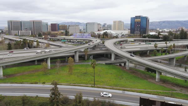 Drone shot of vehicles driving on highway interchange with downtown in ...
