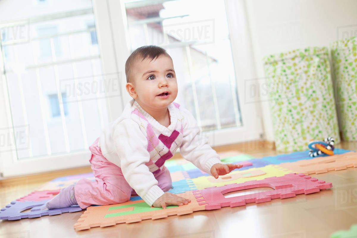 Bavaria, Baby girl crouching on puzzle - Stock Photo - Dissolve