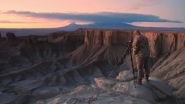 Man standing on cliff at Moonscape overlook during sunrise as he take ...