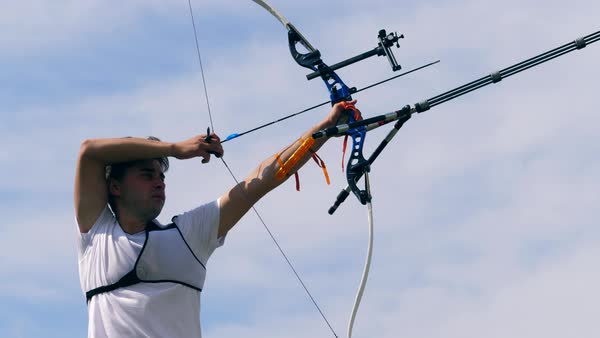 Young man pulling an arrow in a bow on shooting range - Stock Video ...