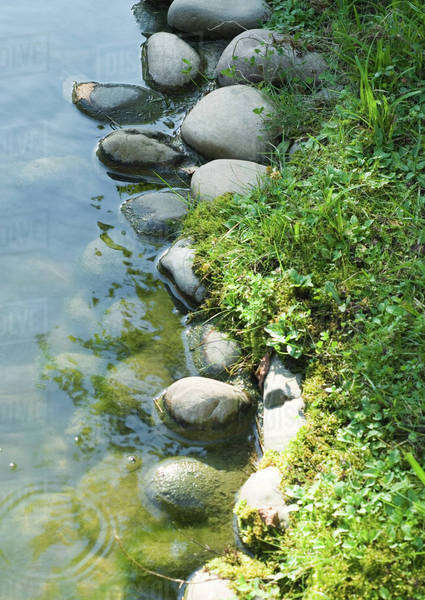 Pebbles lining edge of manmade pond, close-up - Royalty-free Stock ...