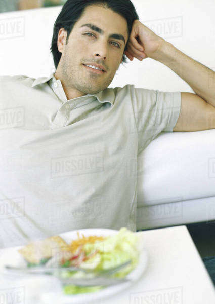 Man sitting at table, with meal, leaning back and looking away ...