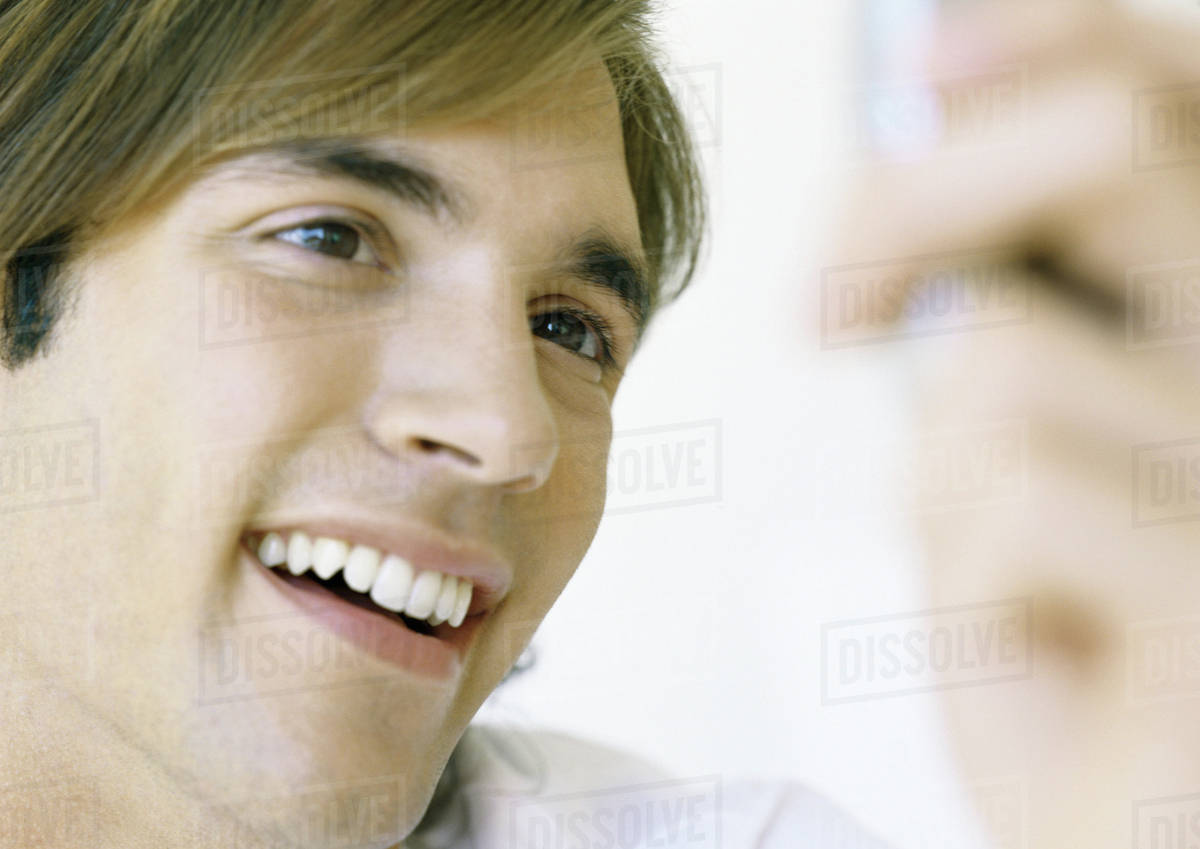 Man smiling, looking at cell phone in blurred foreground - Stock Photo ...