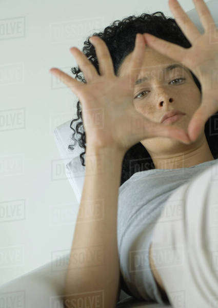 Woman lying down, making frame with hands - Stock Photo - Dissolve