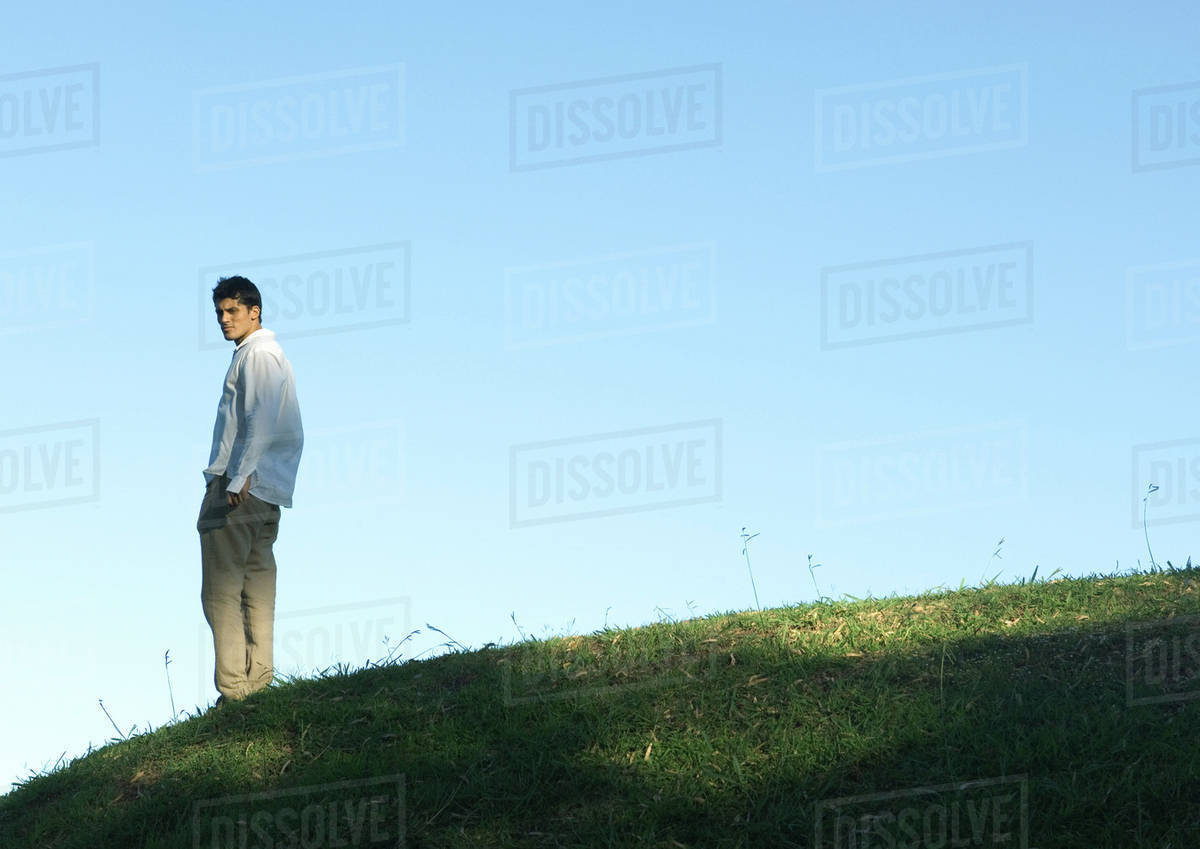 Man standing on hill, looking over shoulder toward camera - Royalty ...