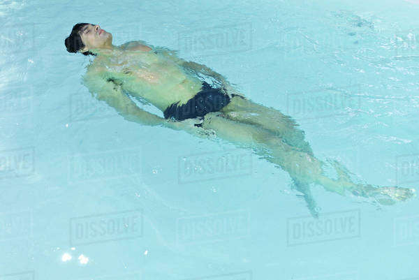 Man floating on back in swimming pool, eyes closed - Stock Photo - Dissolve