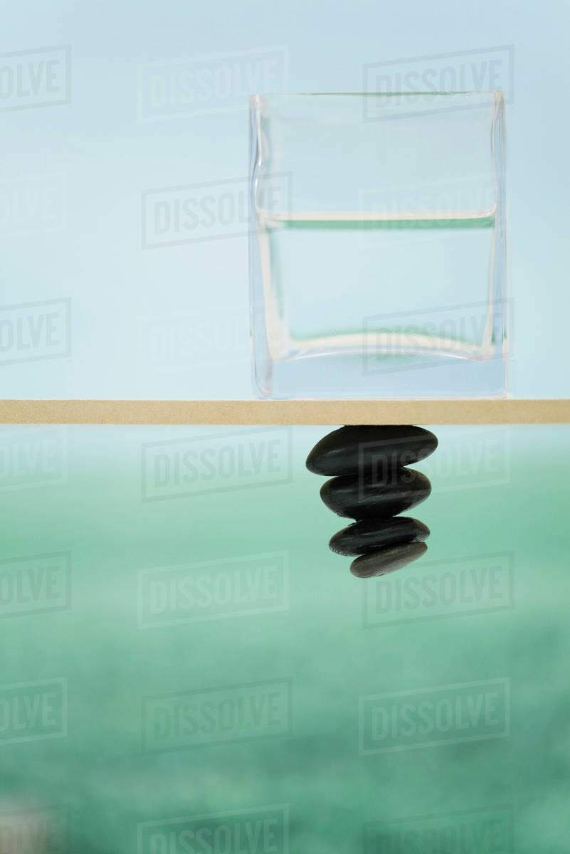 Glass container filled with water sitting on ledge, pile of stones ...