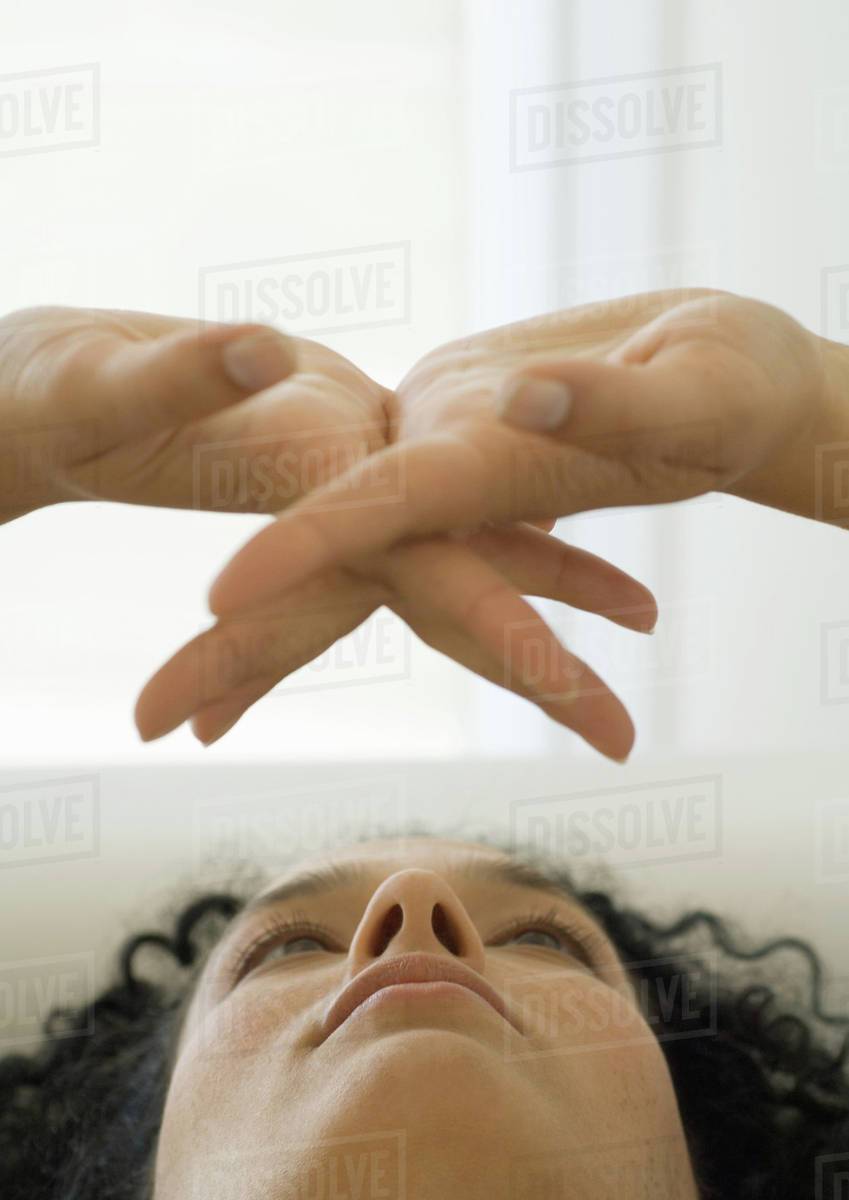 Woman looking at her clasped hands, close-up - Stock Photo - Dissolve