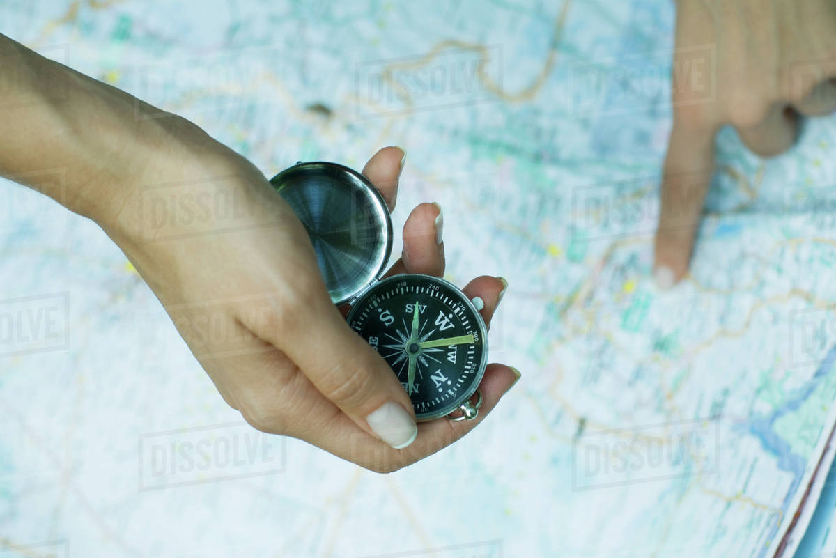 Woman pointing to map and holding compass, close-up - Royalty-free ...