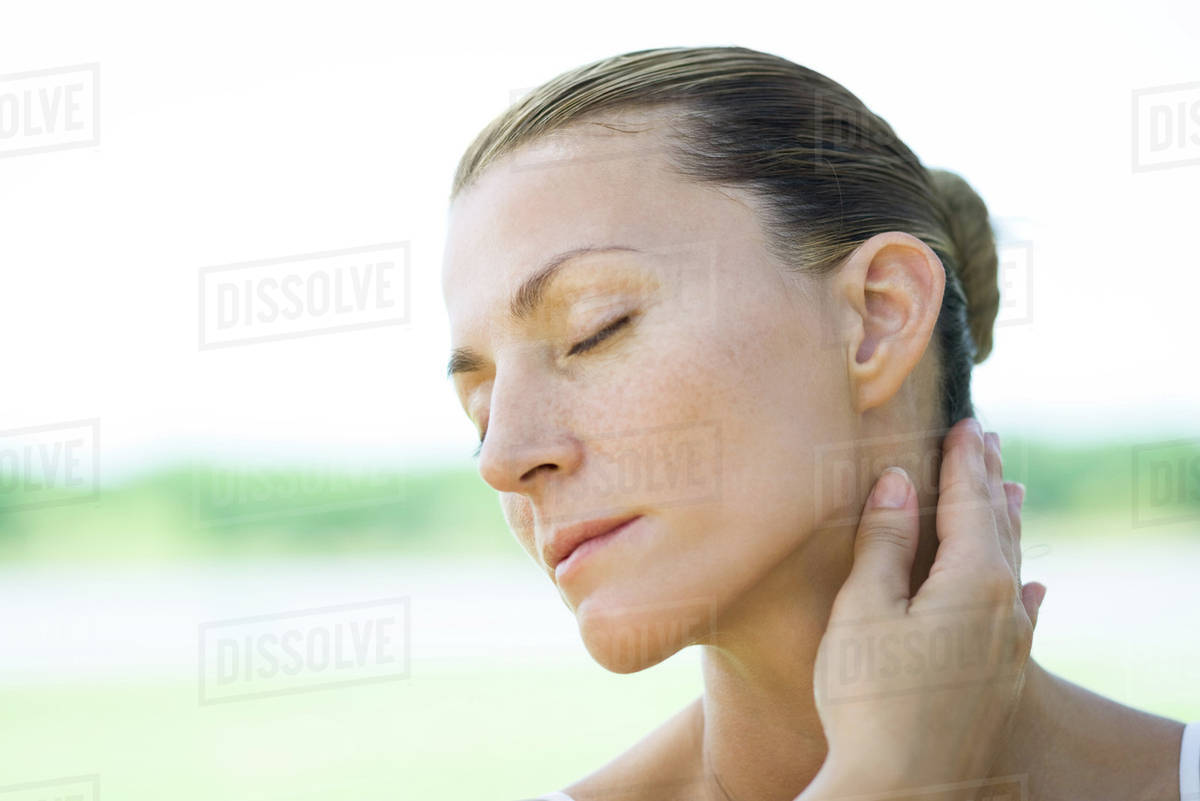 Woman with hand on neck - Stock Photo - Dissolve