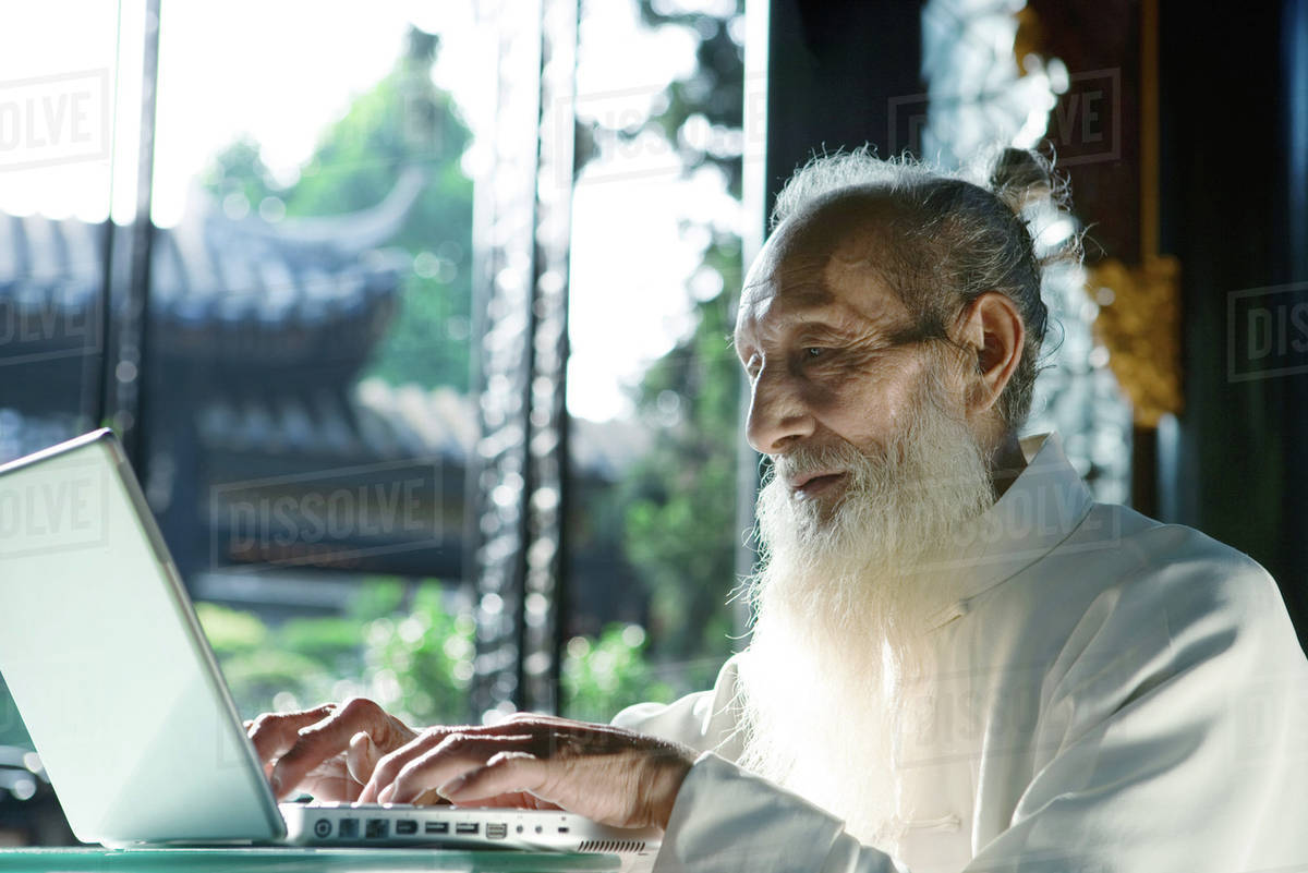 Elderly man wearing traditional Chinese clothing, using laptop - Stock ...