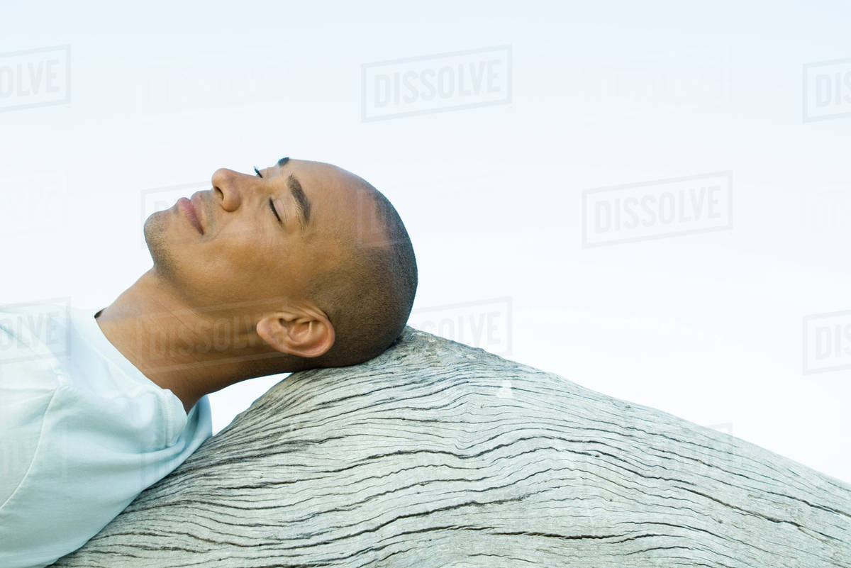 Man leaning back against wood surface, eyes closed - Royalty-free Stock ...