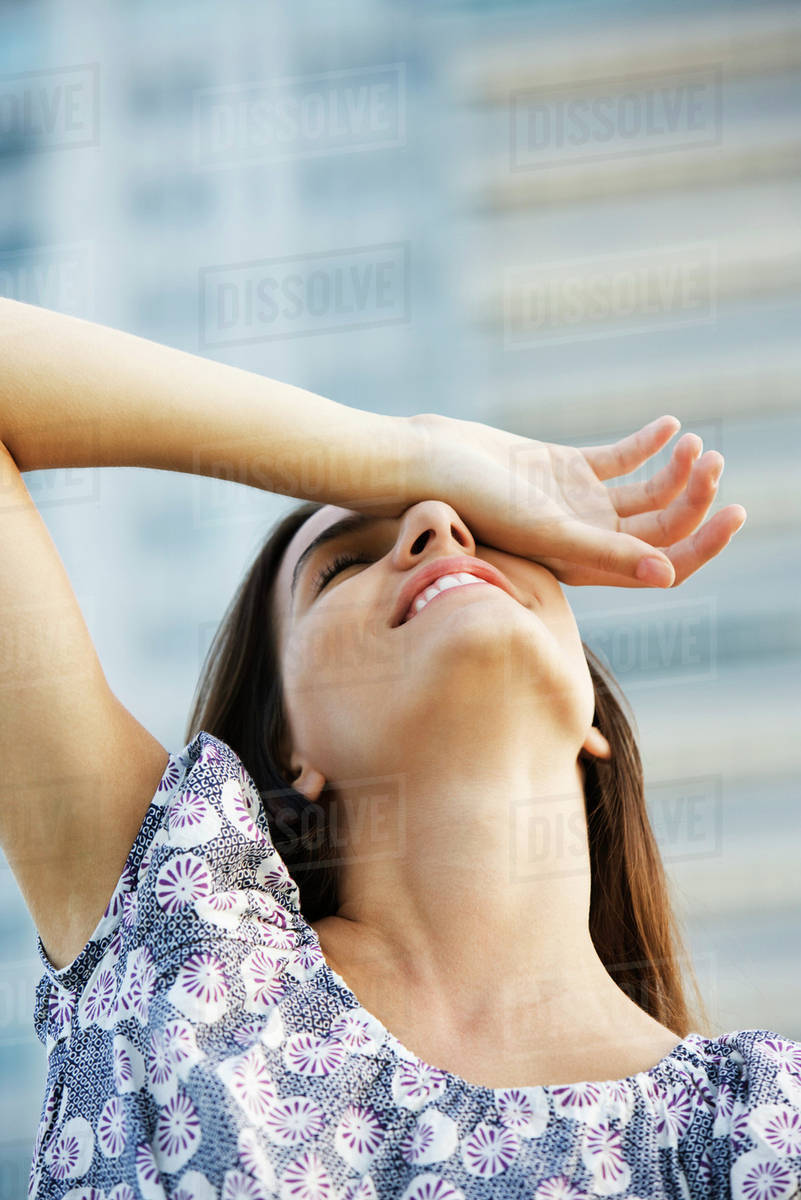 Woman holding back of hand over eye, head back - Stock Photo - Dissolve