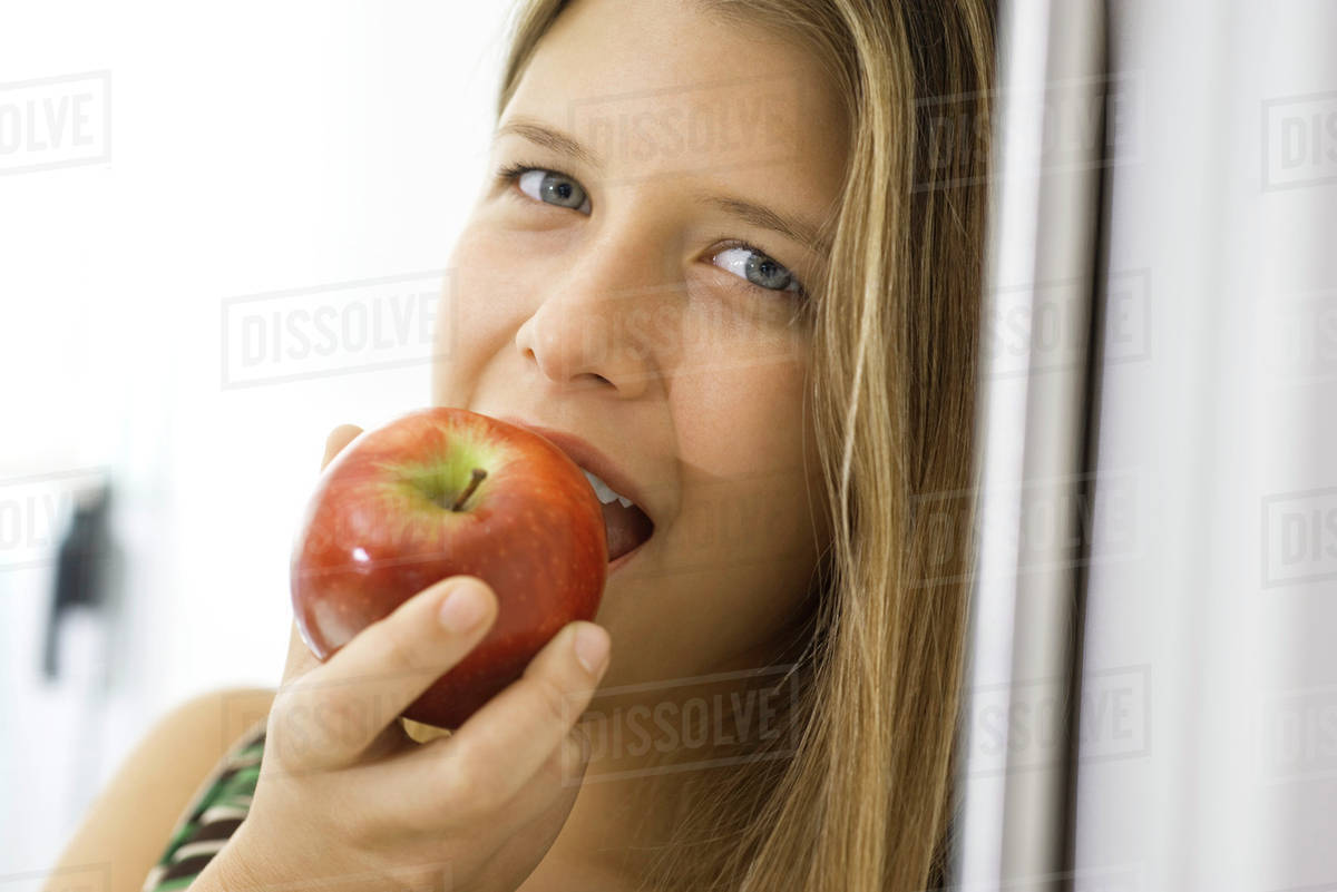 Young woman biting into apple - Stock Photo - Dissolve