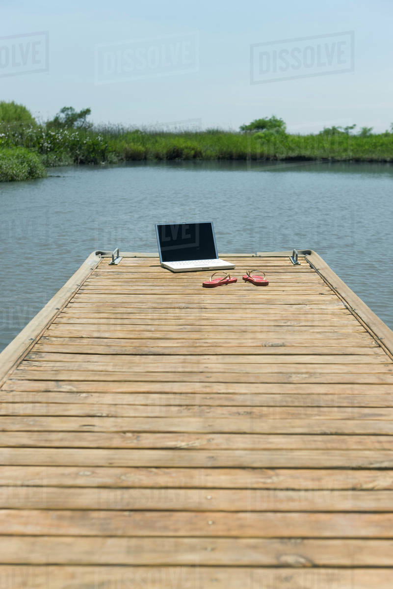 Laptop computer and flip-flops left on dock - Royalty-free Stock Photo ...