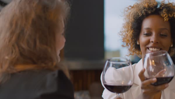 Close up of beautiful elegant women chatting over glass of wine at ...