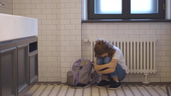 Sad schoolgirl sitting on toilet floor and crying having problems at ...