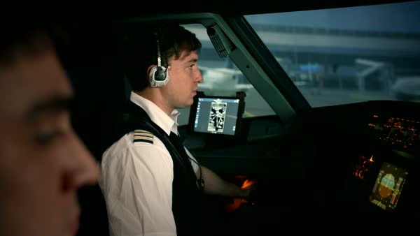 Pilot and co-pilot inside aircraft cockpit preparing for takeoff ...
