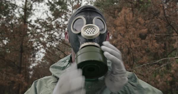 Man in hazmat suit putting on gas mask in forest - Stock Video Footage ...