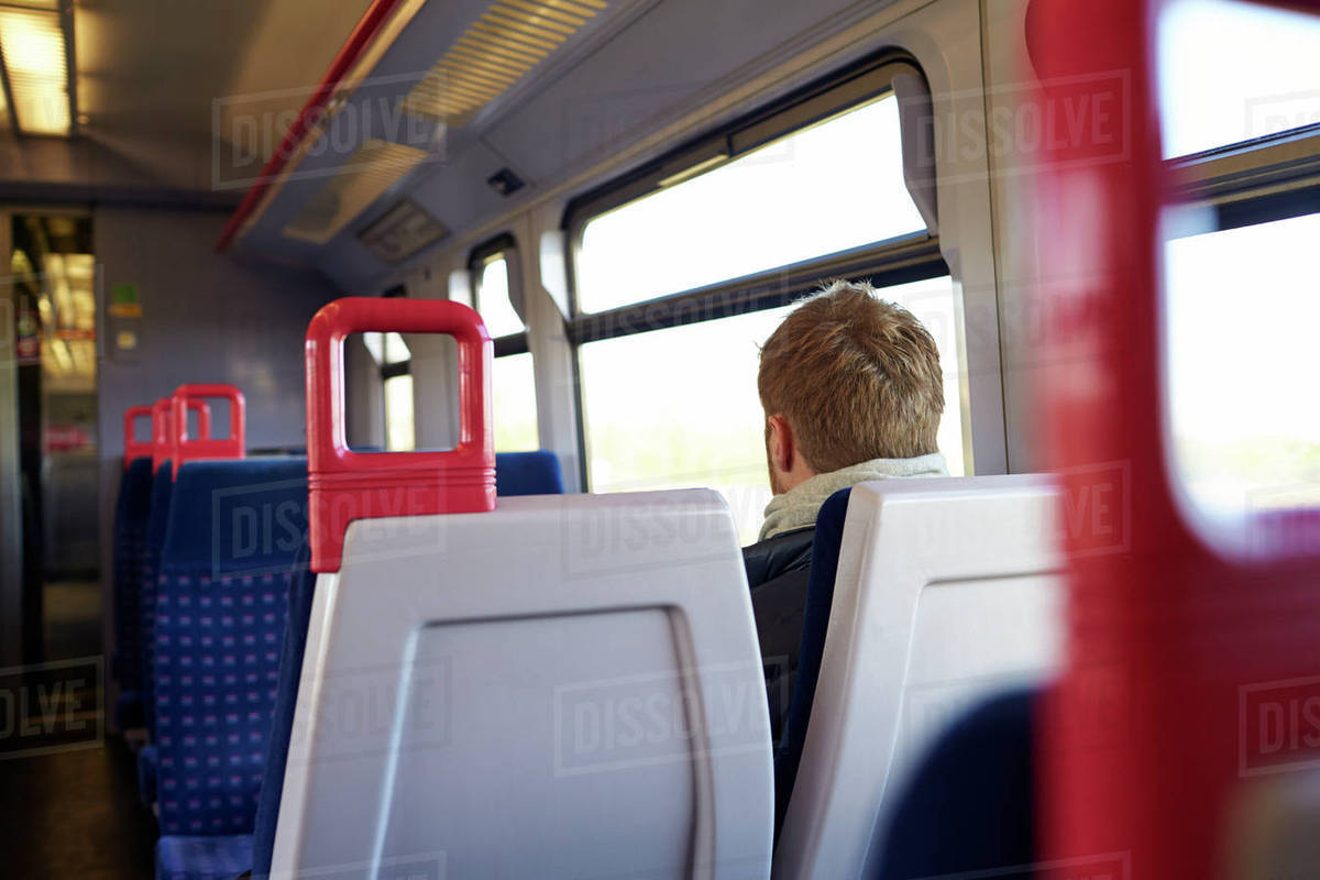Rear view of man sitting in train carriage on rail journey - Stock ...