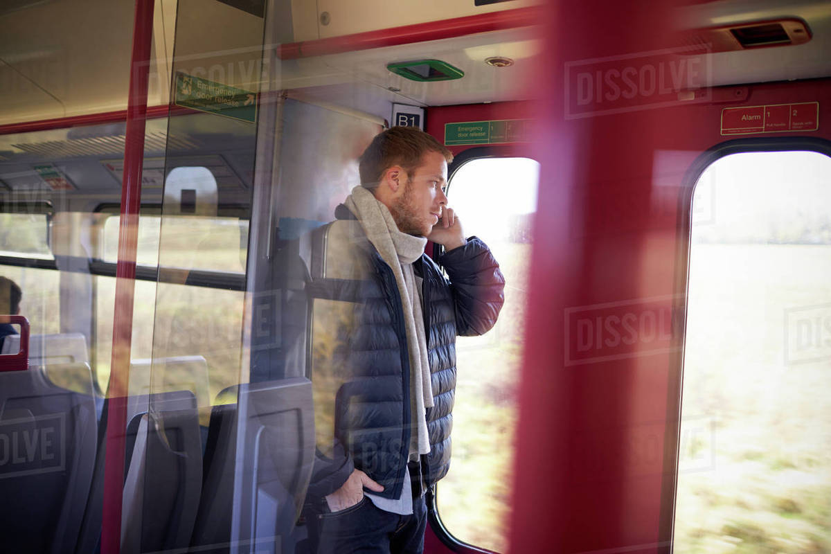 Man standing in train carriage talking on mobile phone - Stock Photo ...