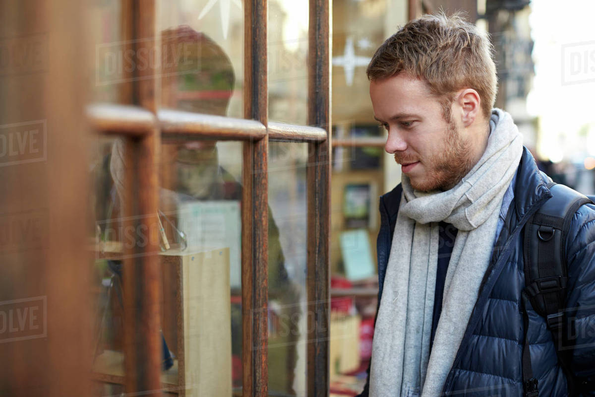 Young man looking in shop window in town centre - Royalty-free Stock ...