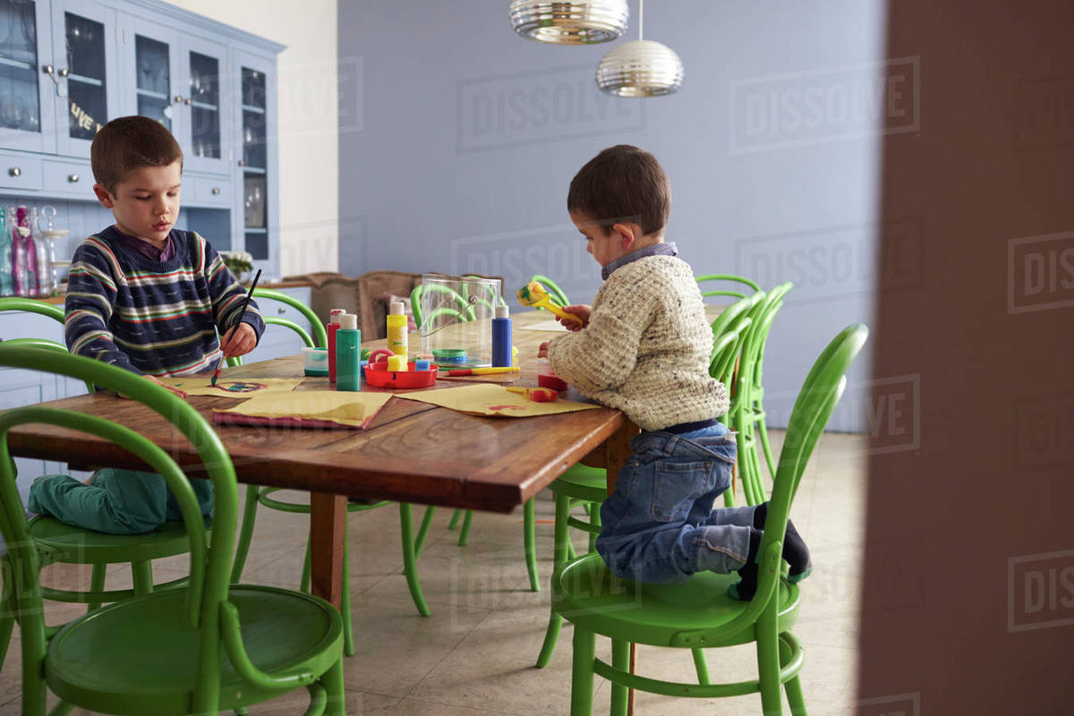 Two young boys sitting at kitchen table and painting picture - Royalty ...