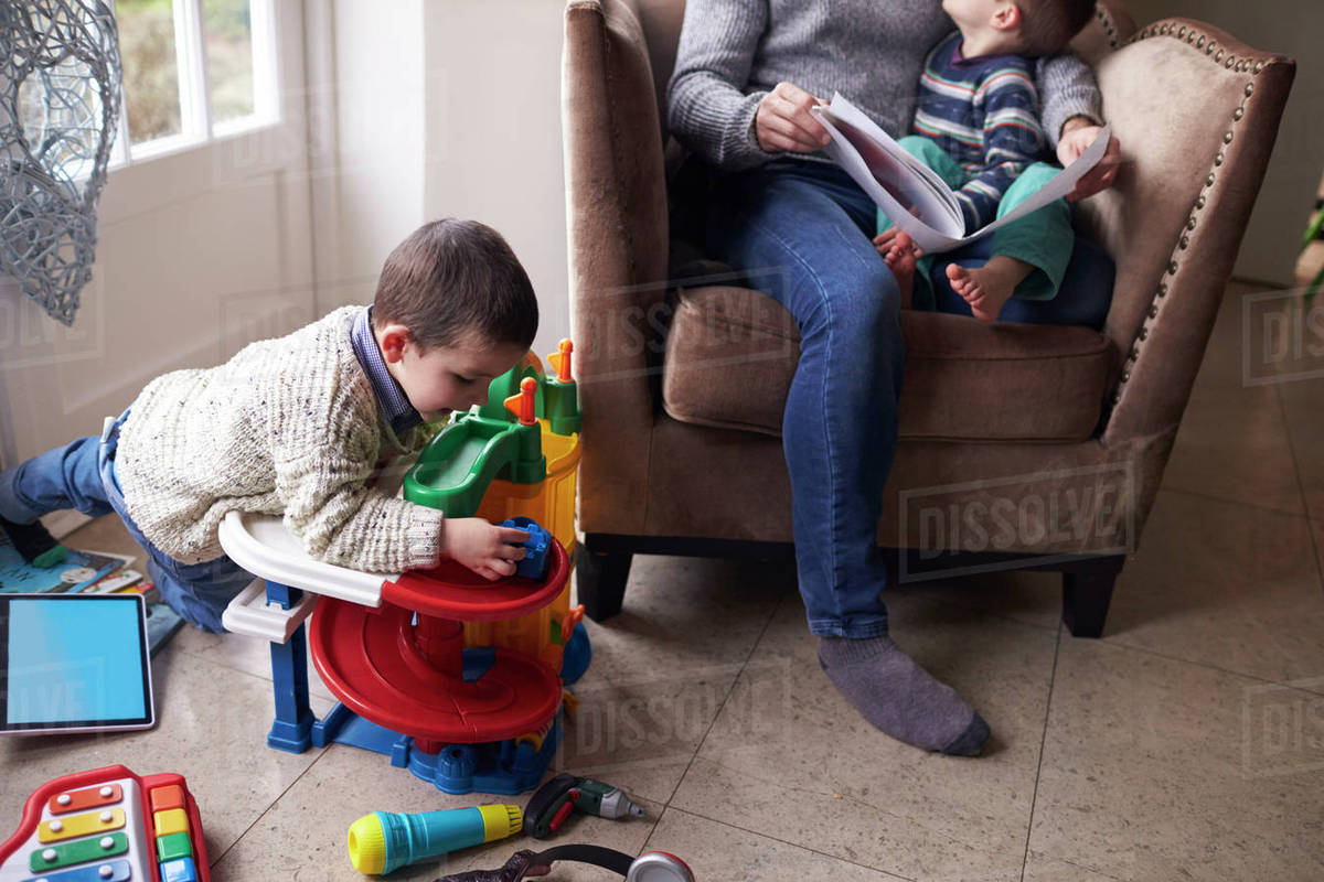 Father sitting in chair at home reading story to sons - Royalty-free ...